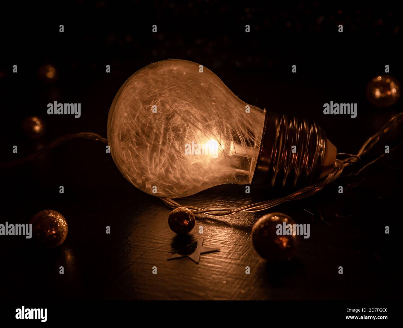 Close up of a light bulb containing tiny white feathers laying on a ...