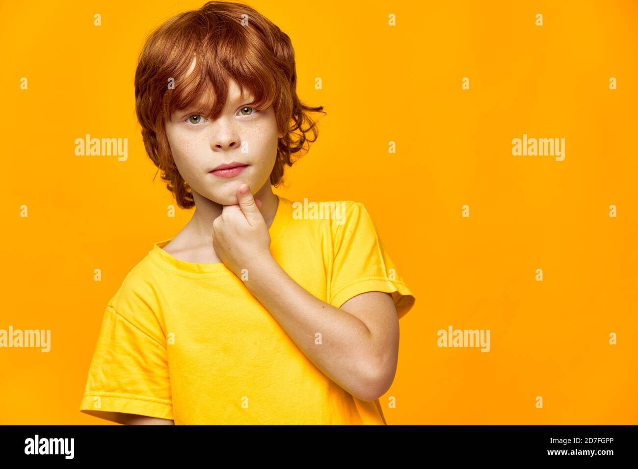 Handsome boy on a yellow background holds a hand near the face of a red ...