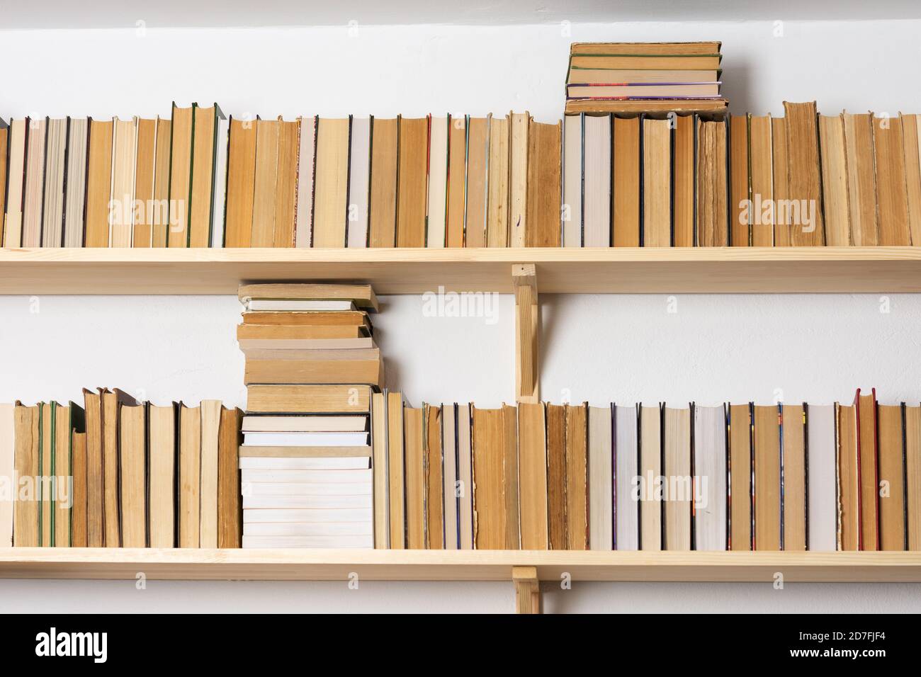 Light wooden bookshelves with hardback overturned books in white ...