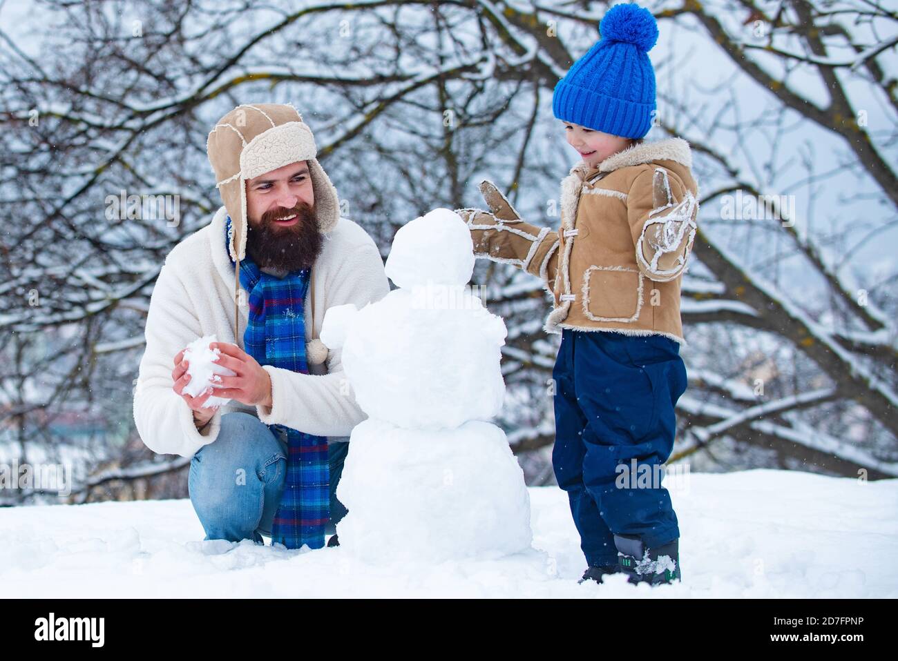 Happy father and son making snowman in the snow. Handmade funny snow ...