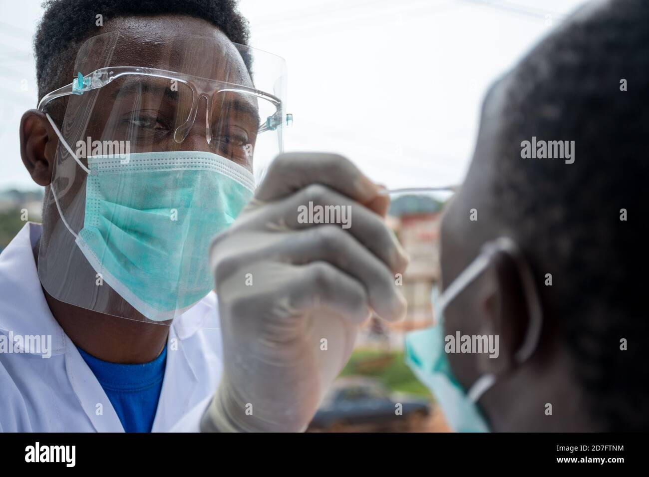 a black lab scientist taking nasal sample from a man Stock Photo - Alamy