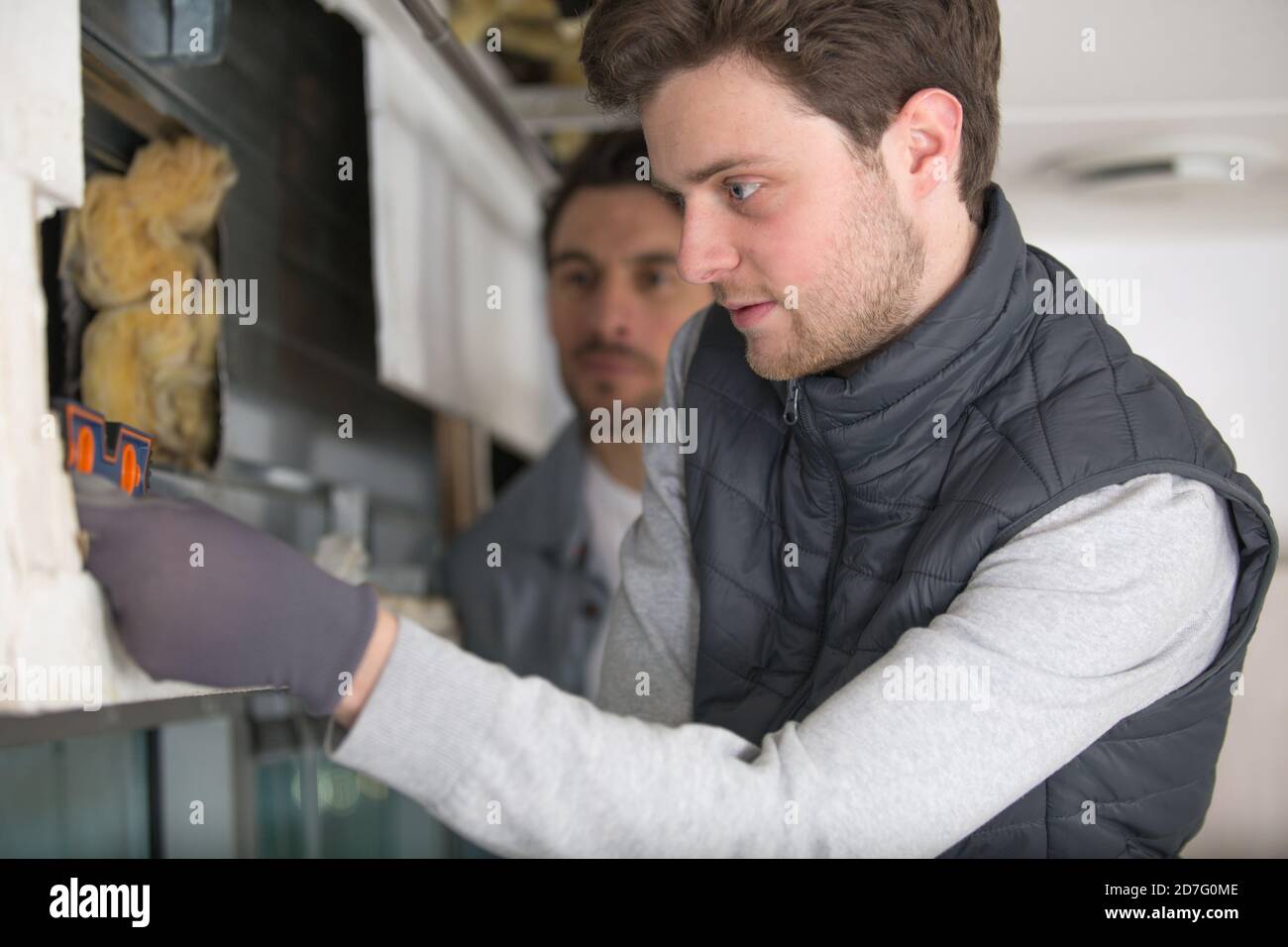 apprentice builder using spirit level under supervision Stock Photo - Alamy