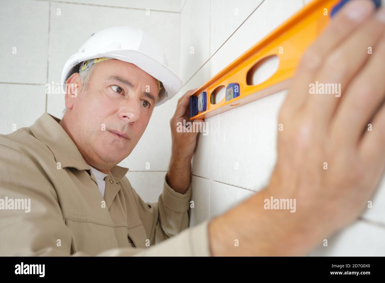 portrait of builder man leveling wall with building tool Stock Photo ...