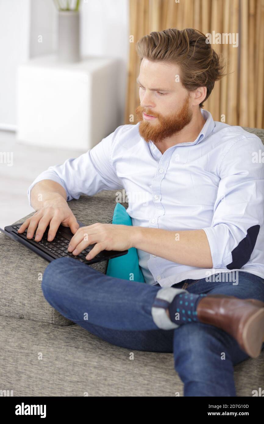 a man is typing keyboard on the sofa Stock Photo - Alamy