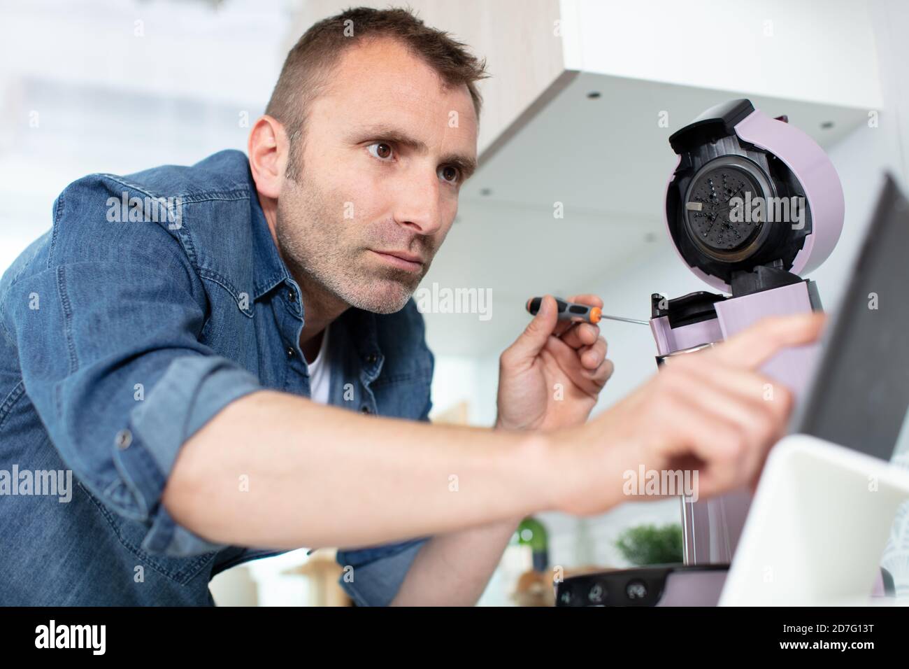 serious man repairing broken coffee machine Stock Photo - Alamy