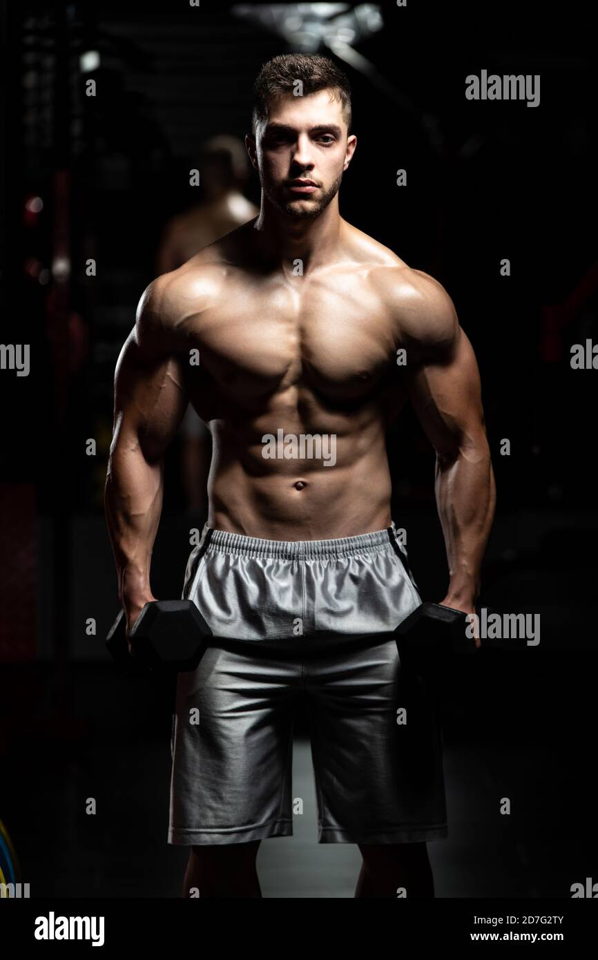 Healthy Man Working Out Biceps In A Dark Gym - Dumbbell Concentration ...