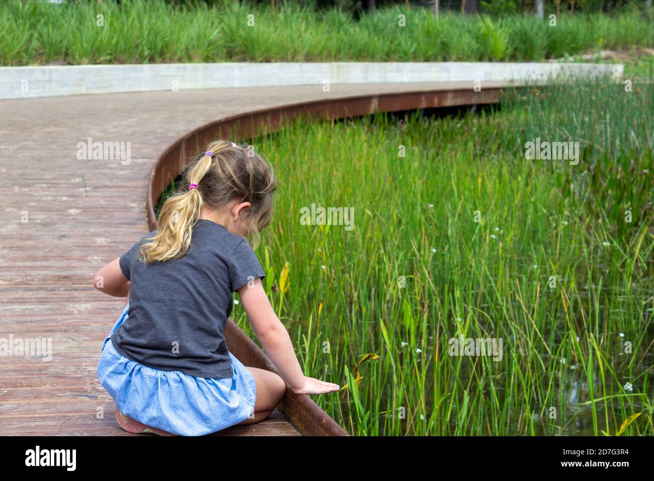 Girl Kneeling by the Water on a Path Stock Photo - Alamy