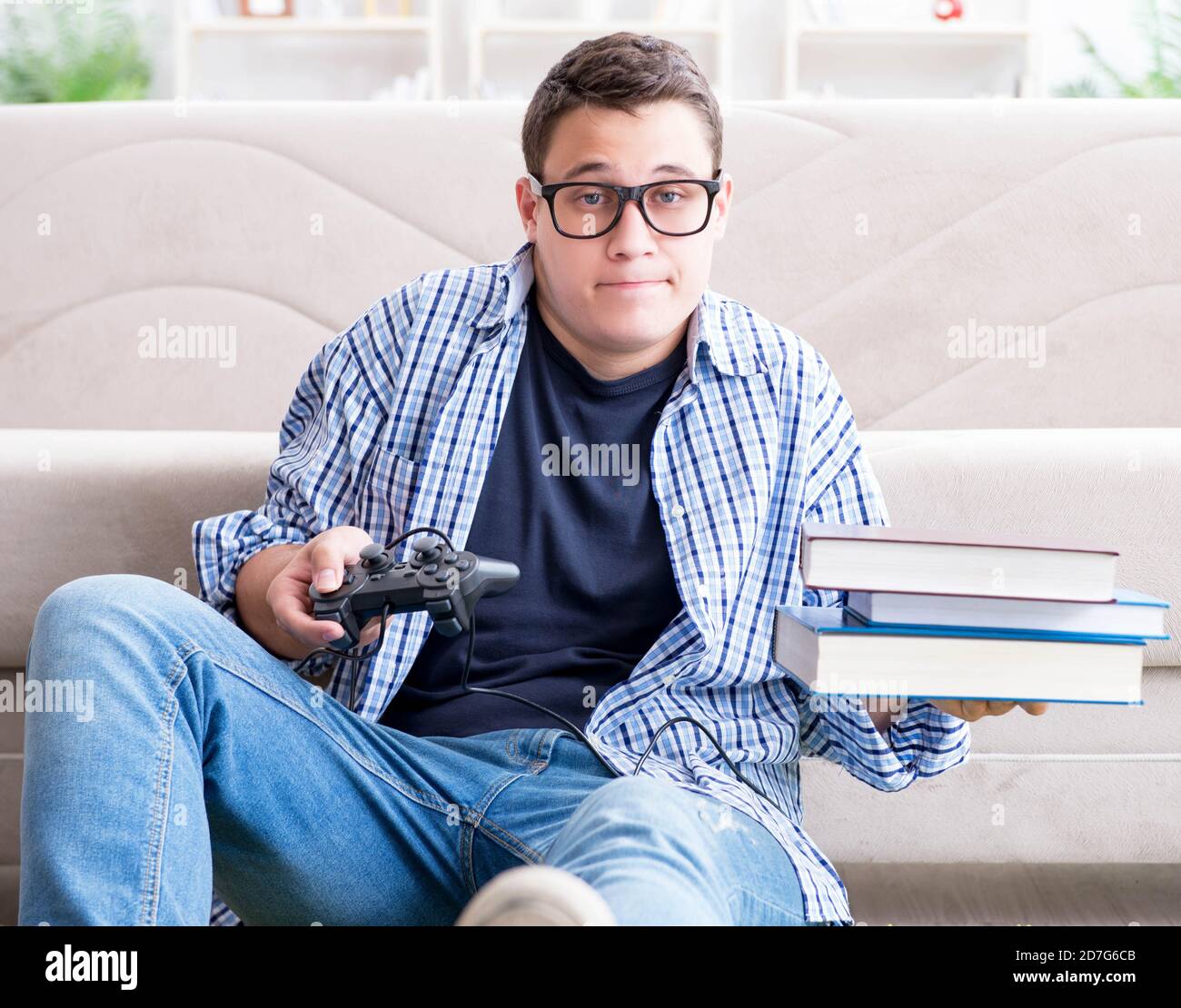 The young student trying to balance studying and playing games Stock ...