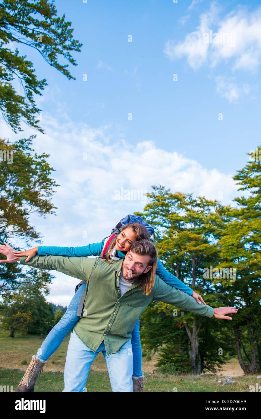 happy couple with backpacks traveling in highlands. Boyfriend carrying ...
