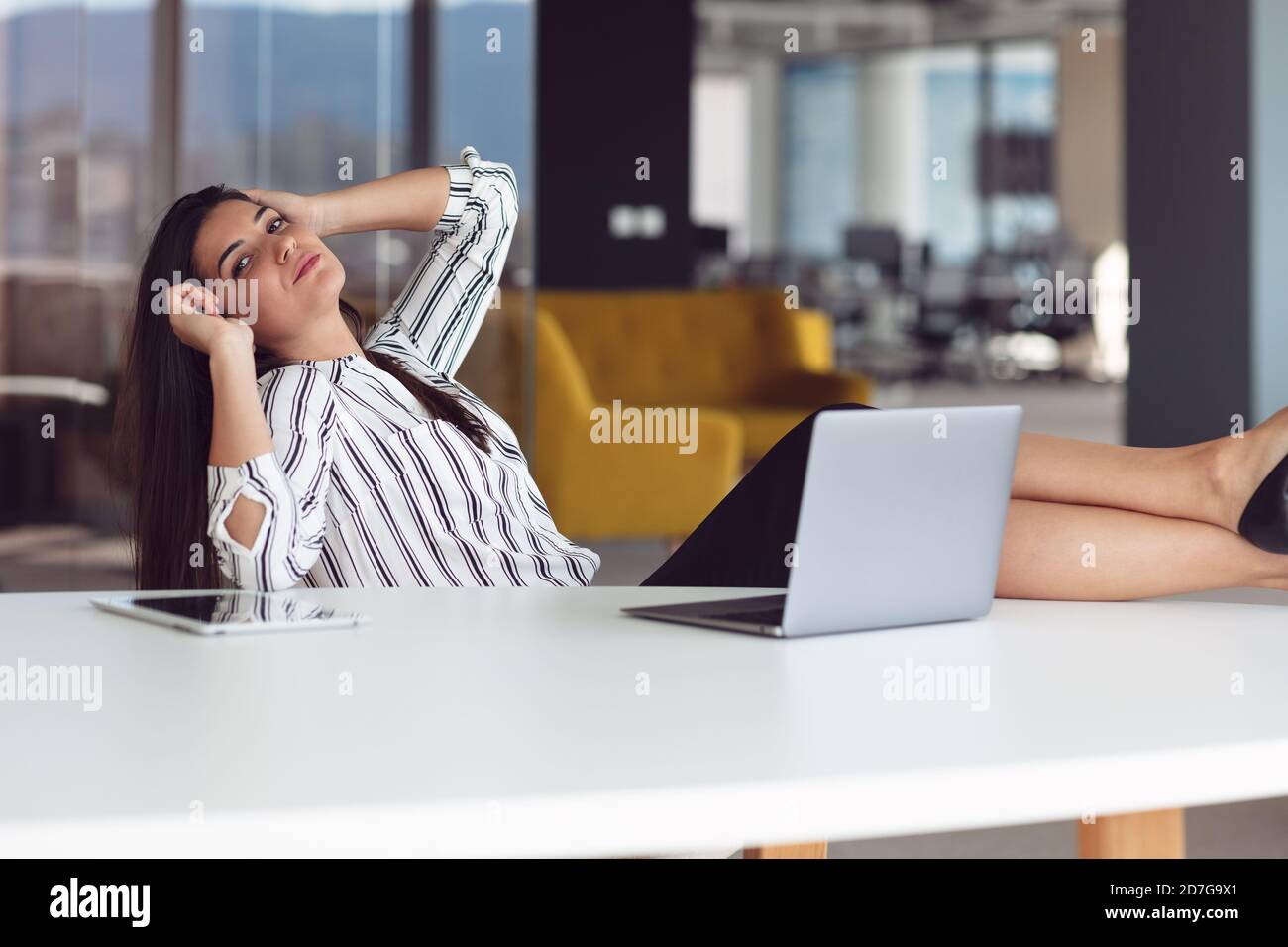 Businesswoman resting relaxing legs on the table hands behind her head ...