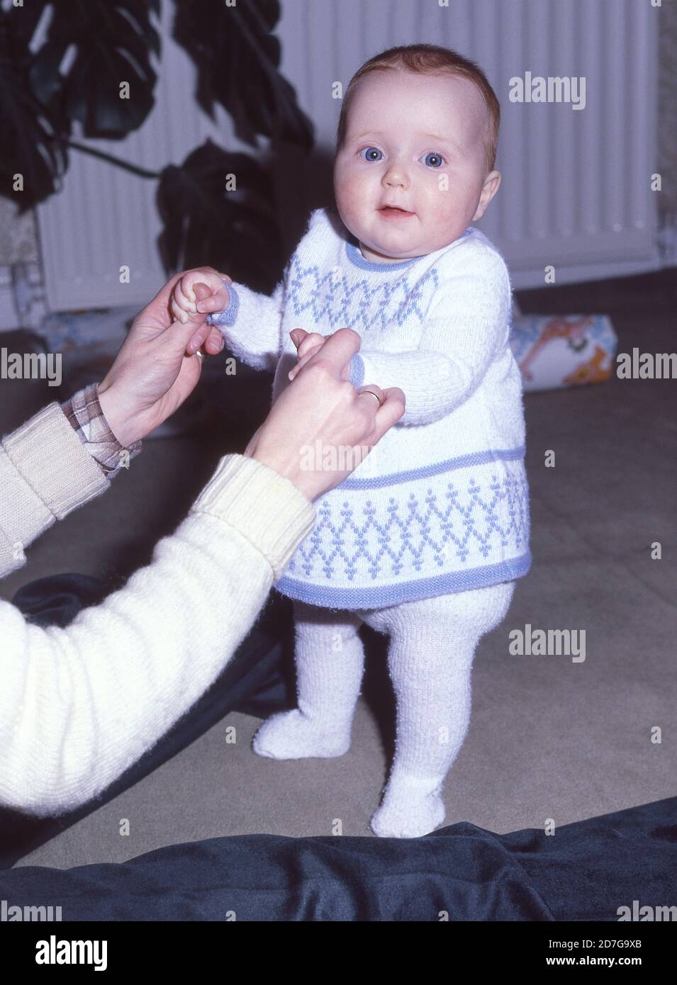 Baby taking her first steps.With a helping hand from her mother Stock ...