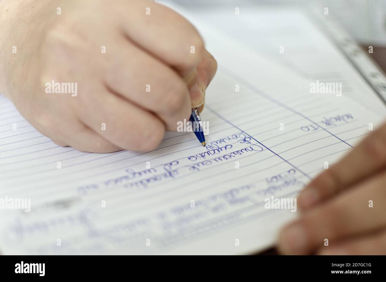 Selective focus shot of female writing cursive on the paper using a ...