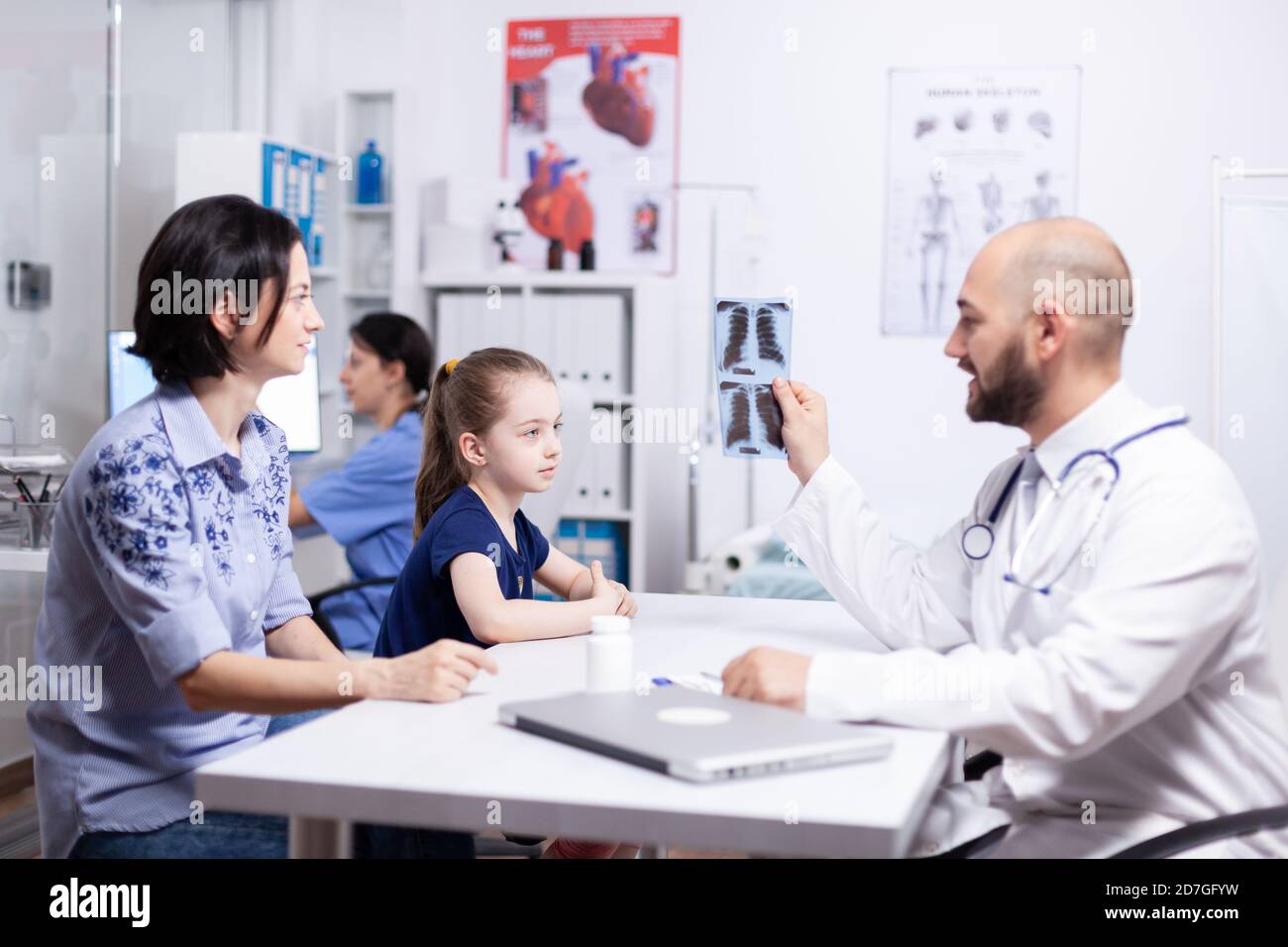 Pediatrician explaining diagnosis to mother and child holding ...
