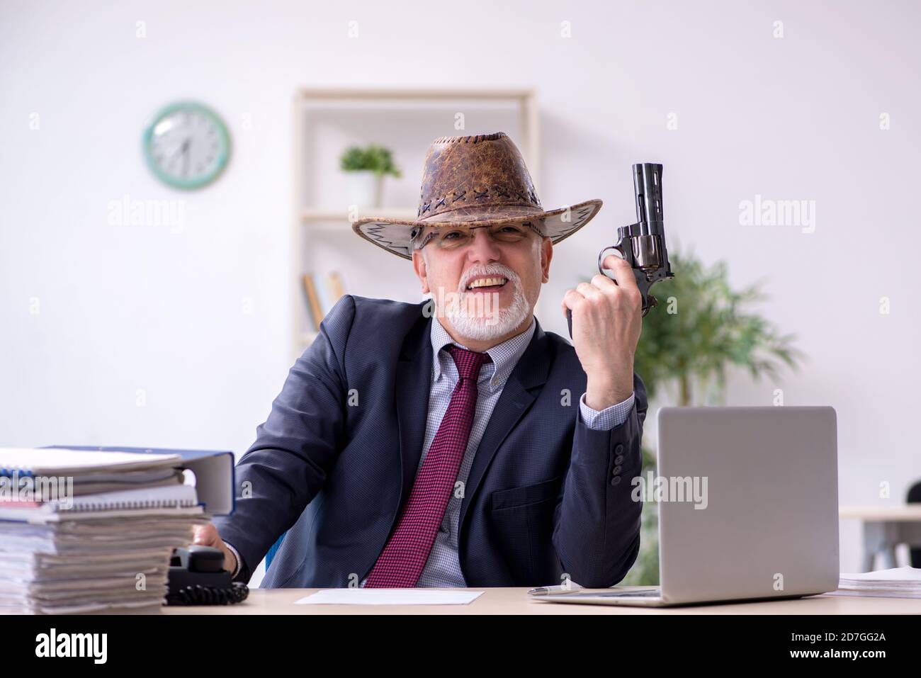 Funny old boss in cowboy hat in office Stock Photo - Alamy