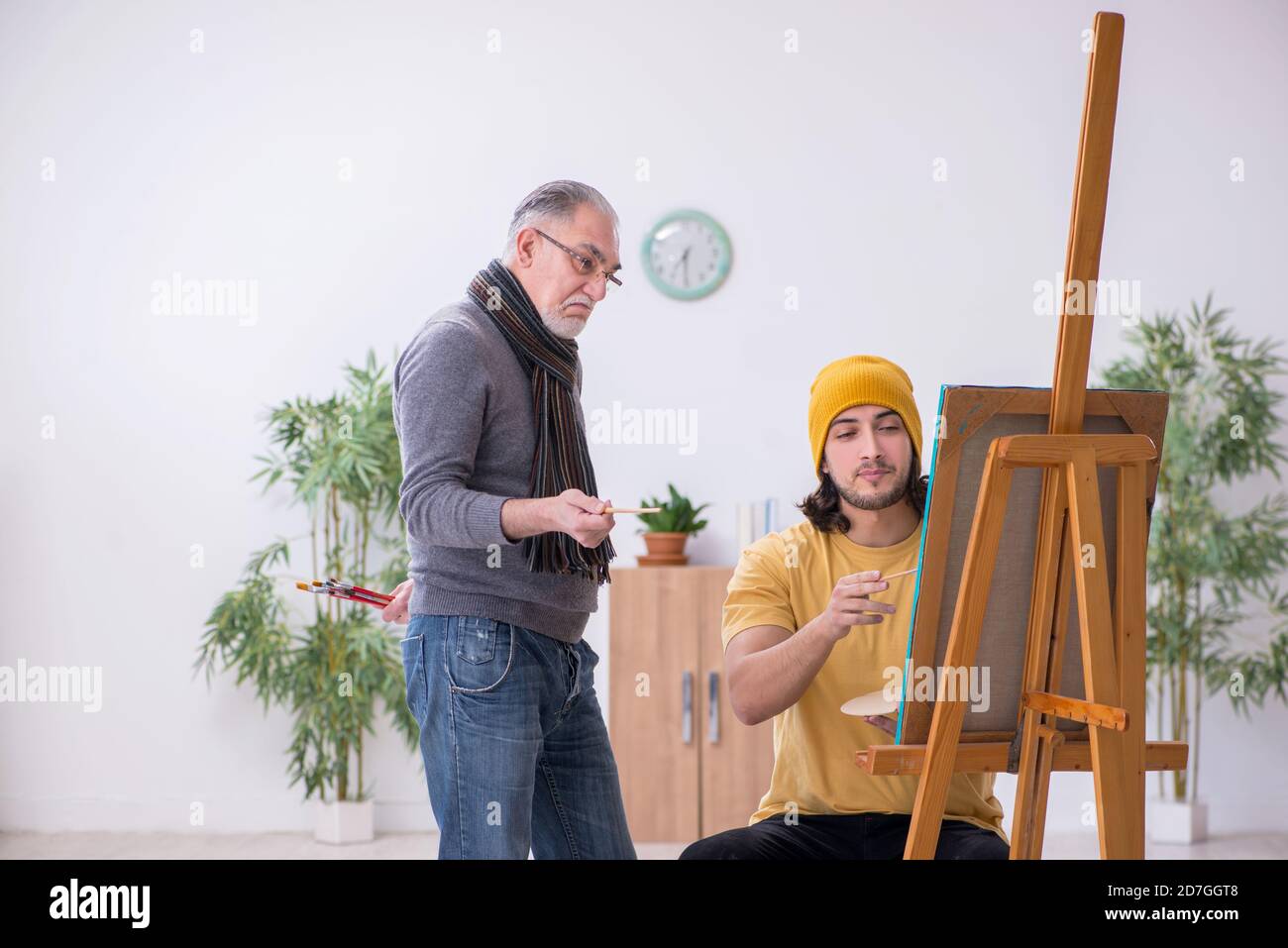 Young man taking lesson from experienced painter Stock Photo - Alamy