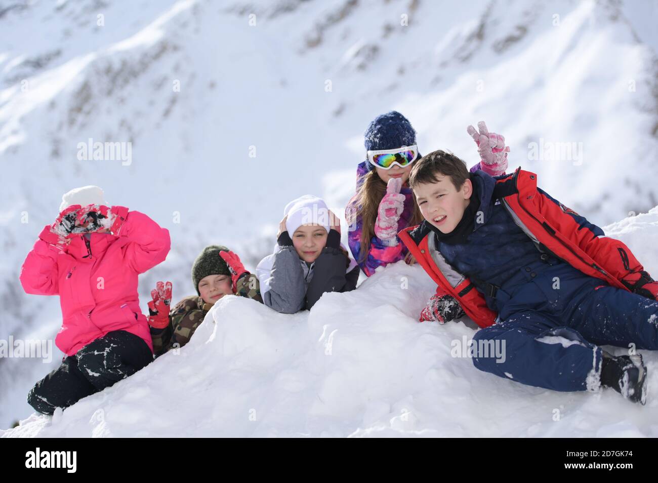 group of five little kids boys and girls in ski suit lying on white ...