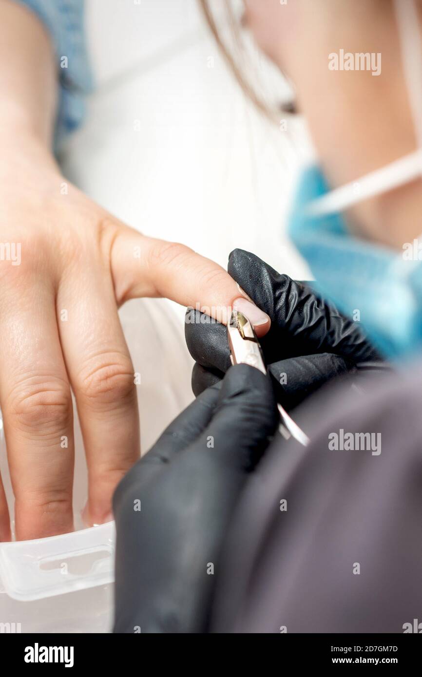 Manicure master removes cuticles by professional nail clipper metal ...