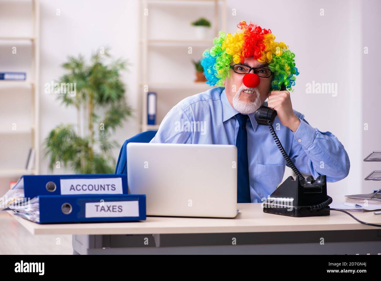 Aged businessman clown working in the office Stock Photo - Alamy