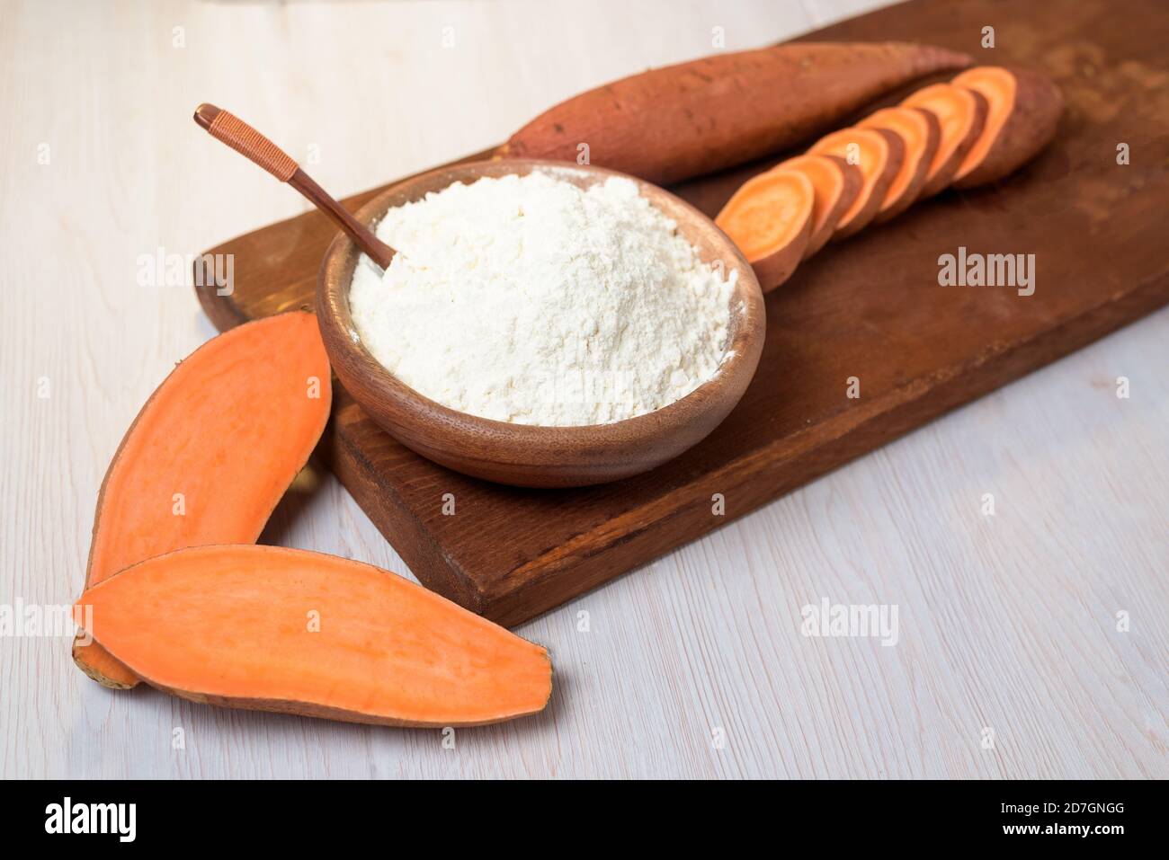 sweet potato flour in a wooden plate on a light background. fresh sweet ...