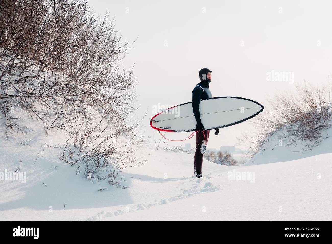 Snowy winter and surfer with surfboard. Winter beach and surfer in ...