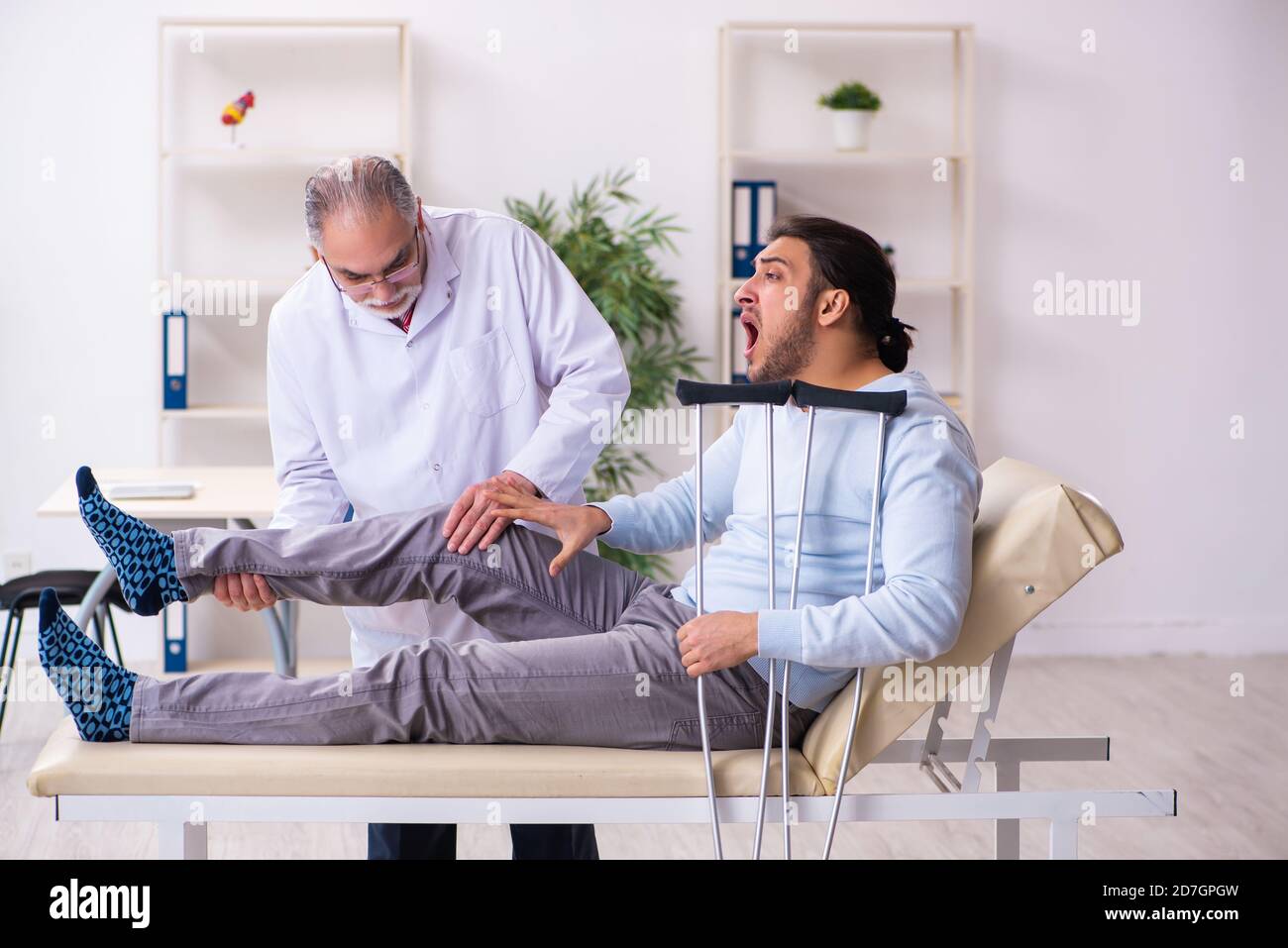 Leg injured man visiting old doctor osteopath Stock Photo - Alamy