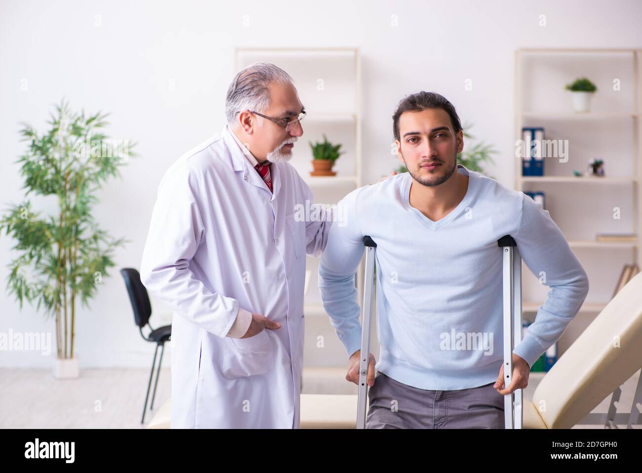 Leg injured man visiting old doctor osteopath Stock Photo - Alamy