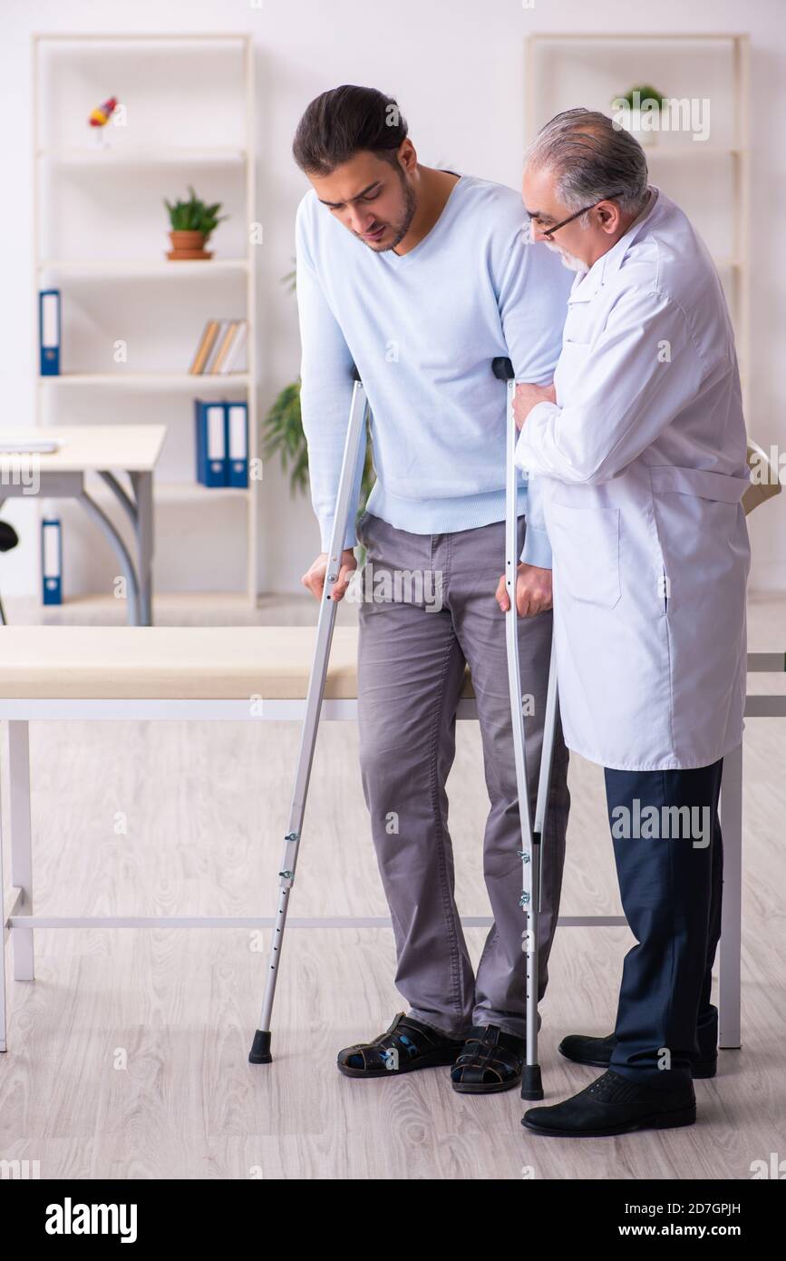 Leg injured man visiting old doctor osteopath Stock Photo - Alamy