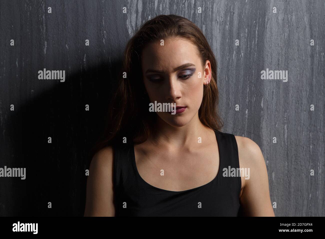 Photo of looking down girl in shadows on grey background Stock Photo ...