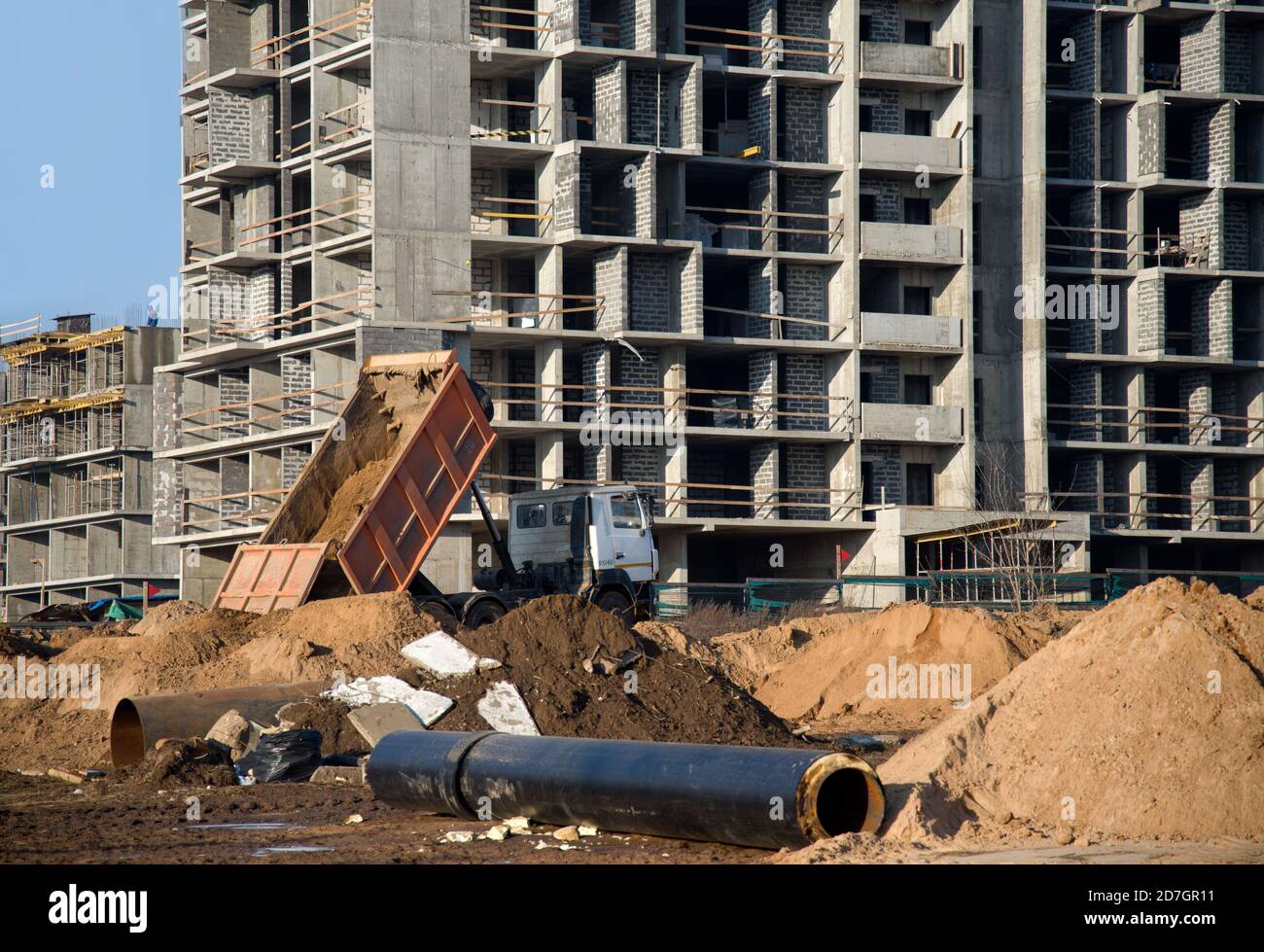 Dump truck dumps its load of sand and soil on construction site for ...