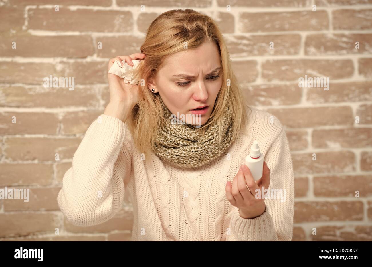 Getting fast relief. Pretty girl with runny nose holding nasal drops ...
