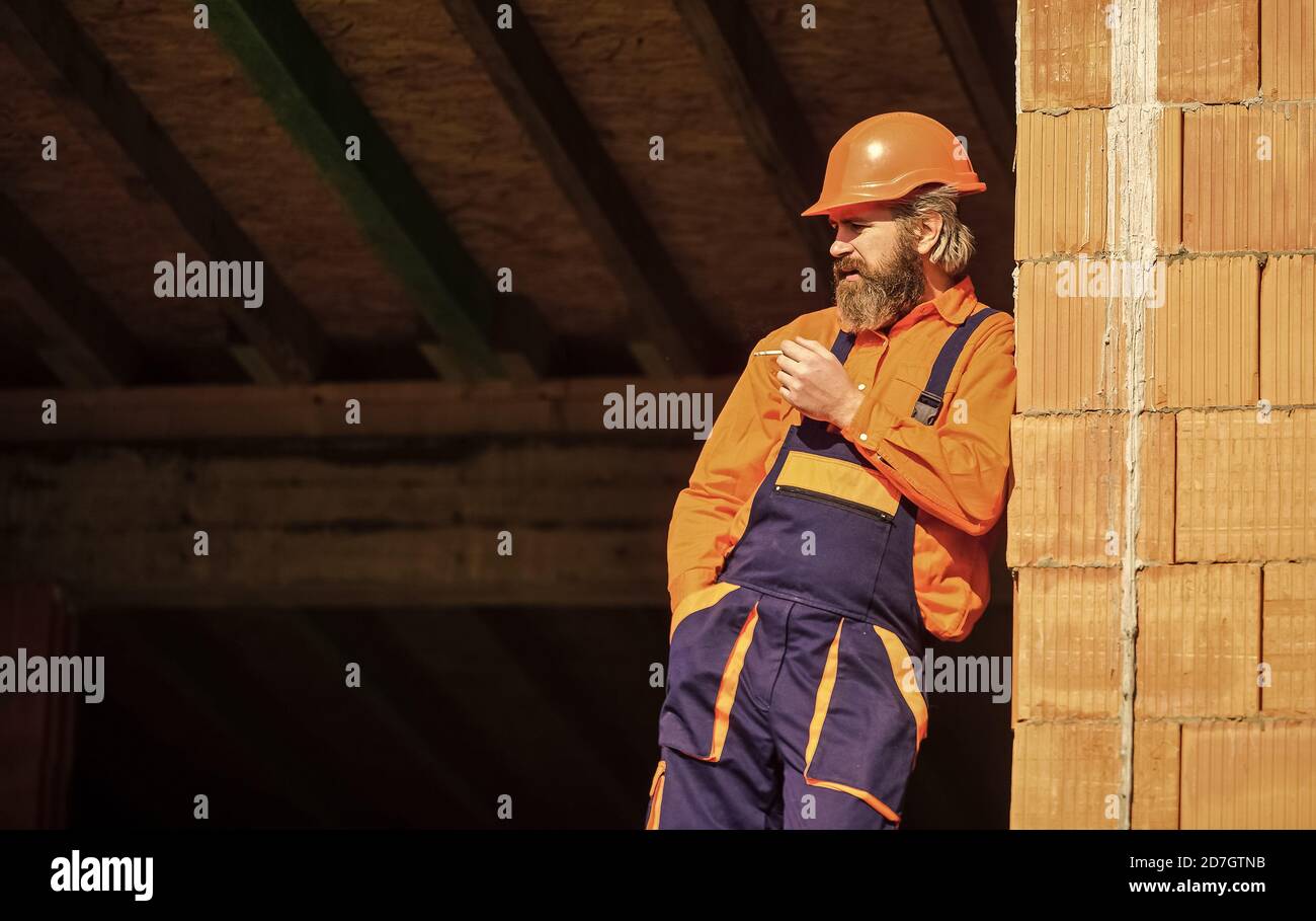 tired builder relax. construction worker smoking cigarette. building is ...
