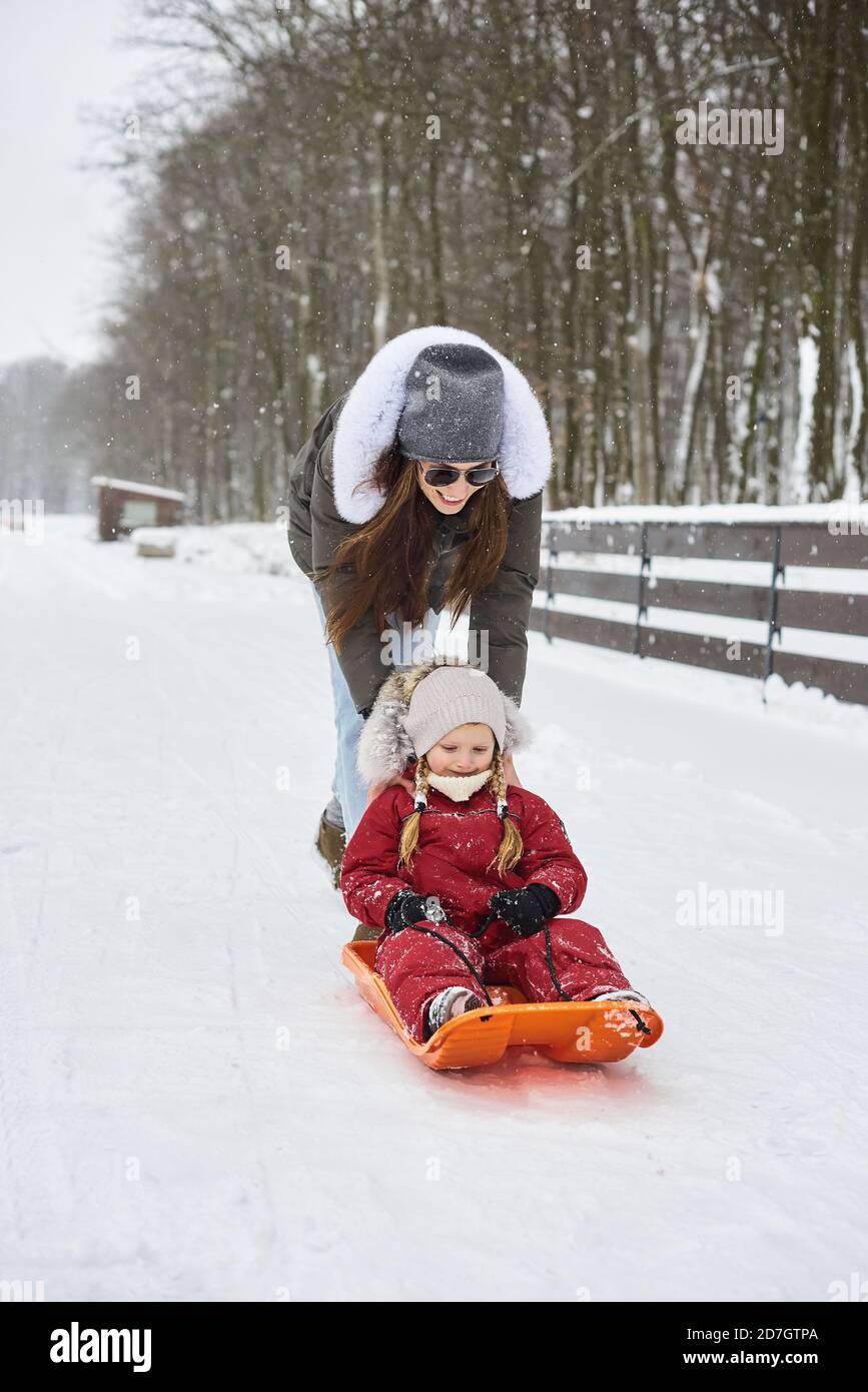 A young beautiful mom sledges her baby Stock Photo - Alamy