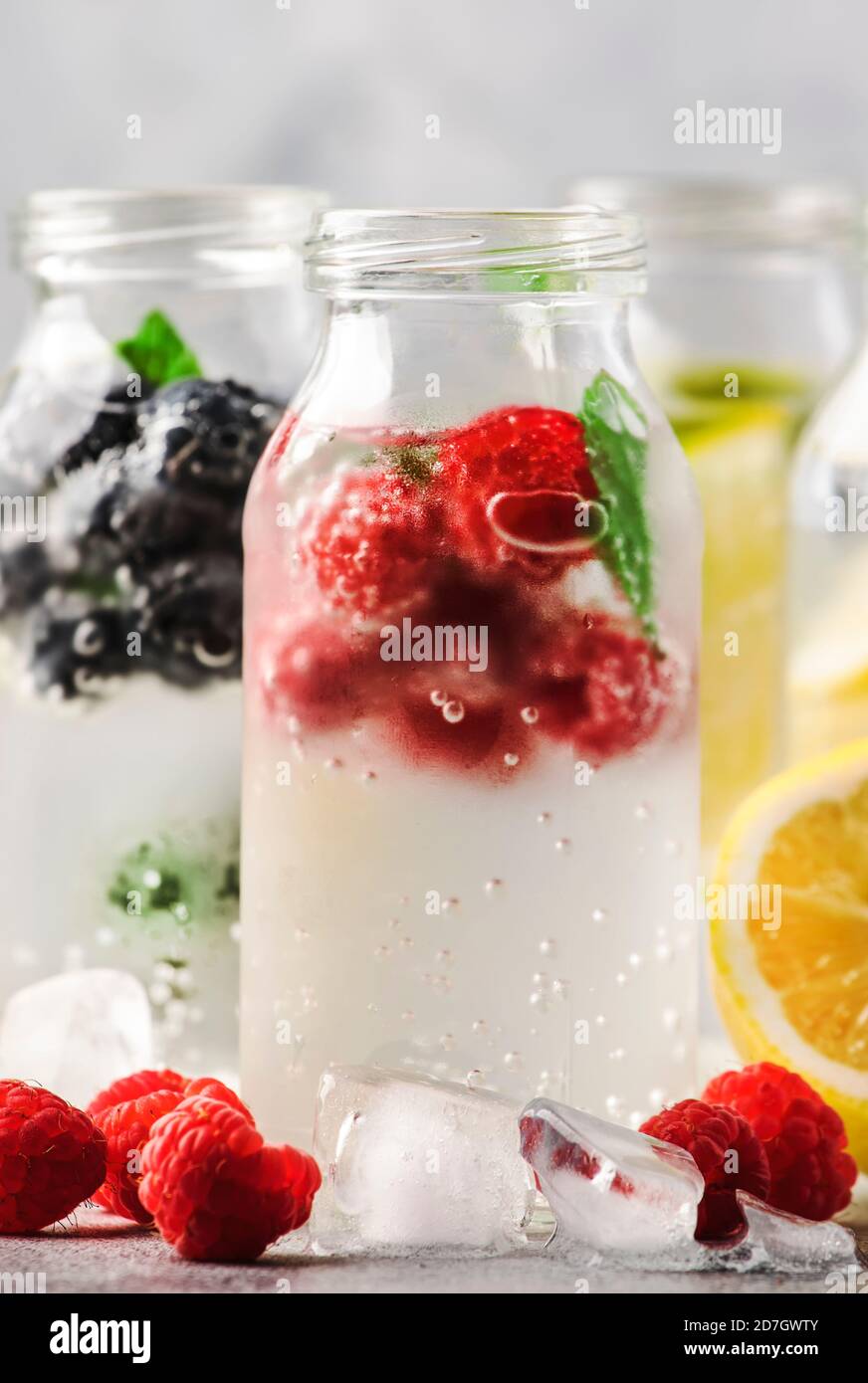 Berry and citrus soft drinks and cocktails in glass bottles on gray ...