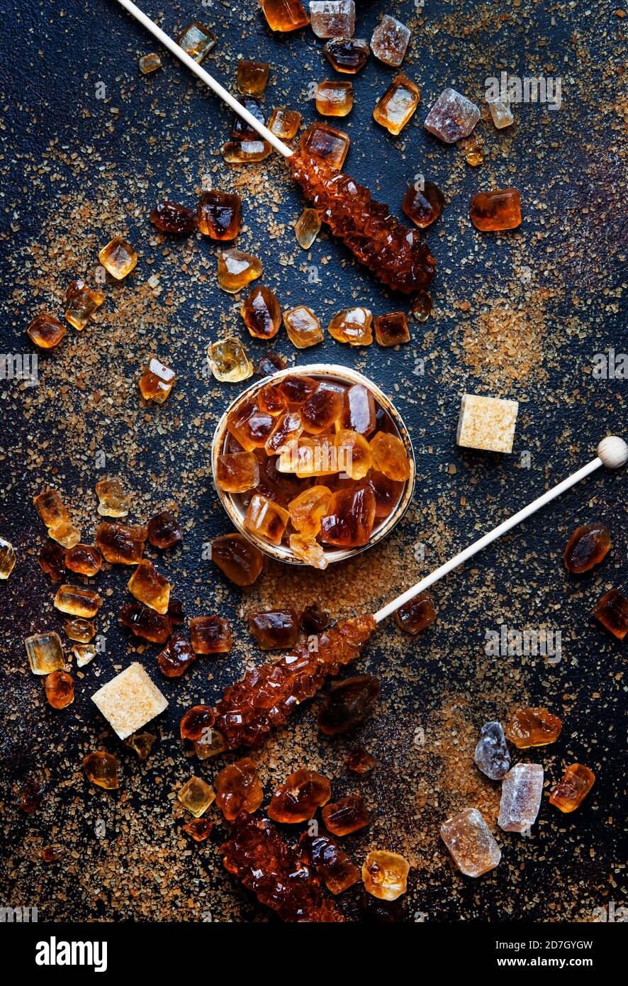 Sweet food background, assorted white and brown sugar on a dark ...