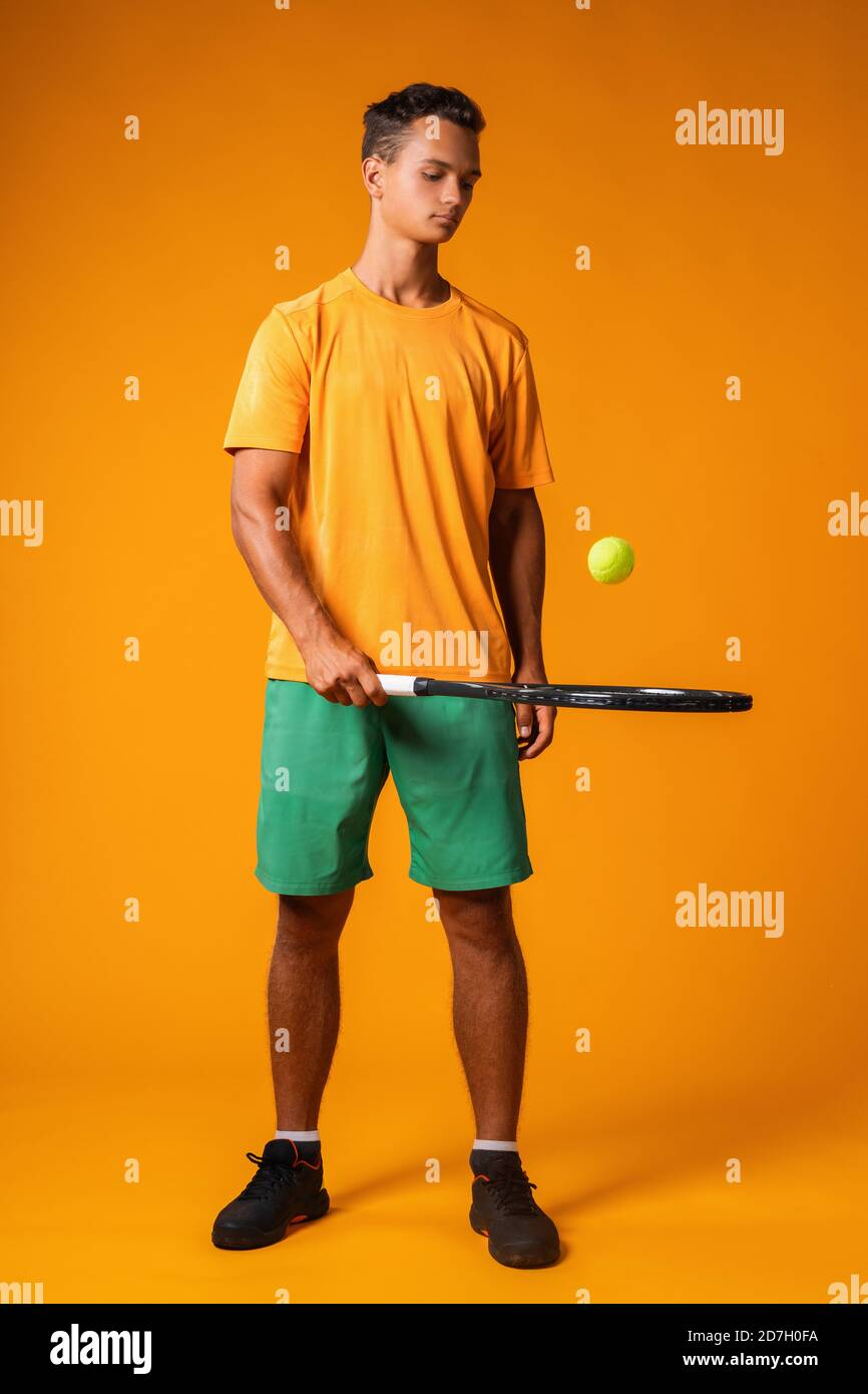 Full-length portrait of a tennis player man in action against orange ...