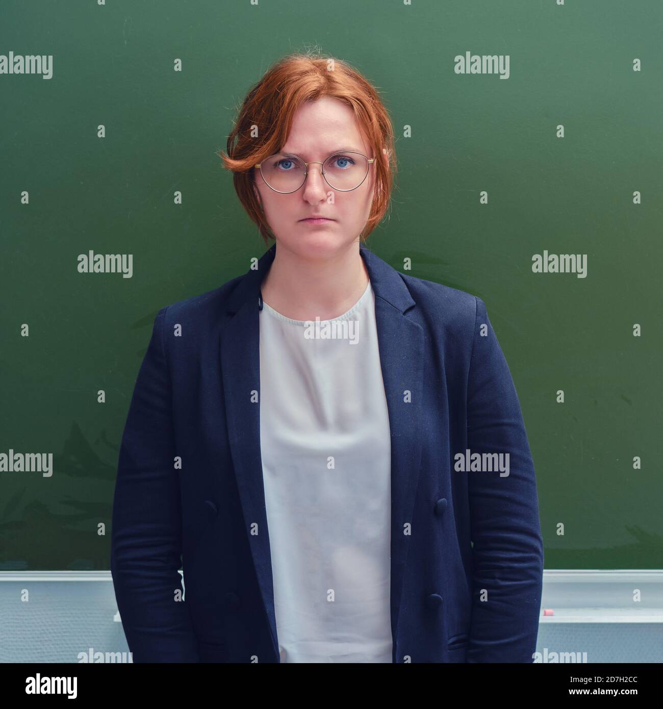 Sad teacher in a suit at the blackboard, close-up. Woman school teacher ...