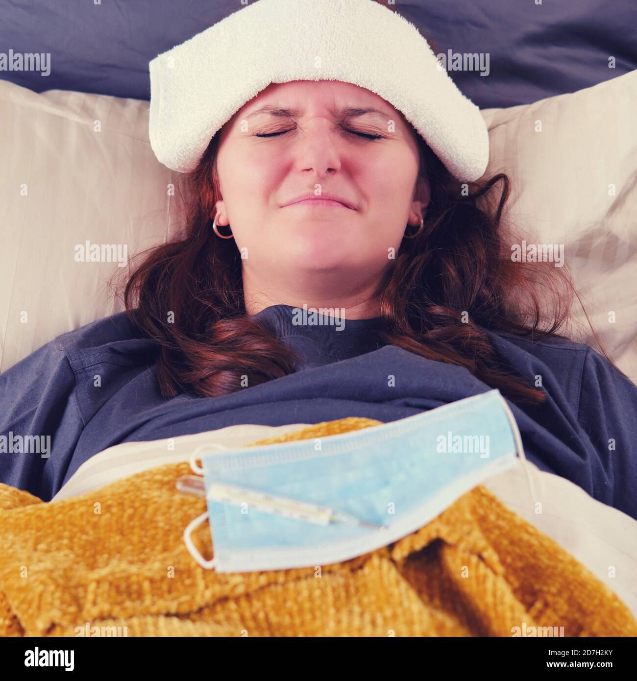 Woman with red hair lies in bed sick with coronavirus with a cold ...