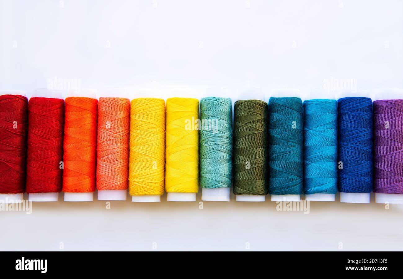 Spools of thread on the colors of the rainbow on a white background ...