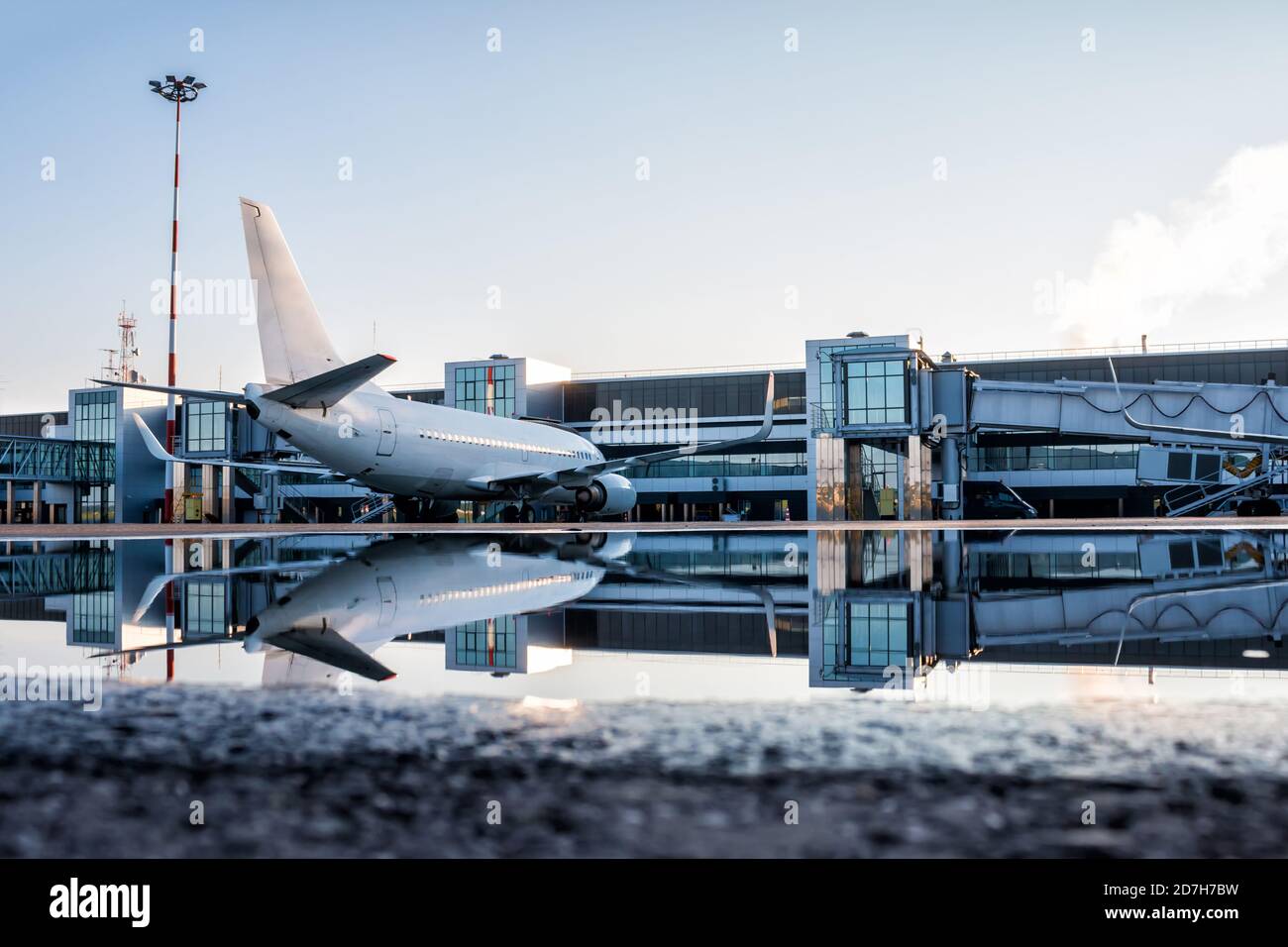 Passenger aircraft parked to a jetway with reflection in a puddle Stock ...