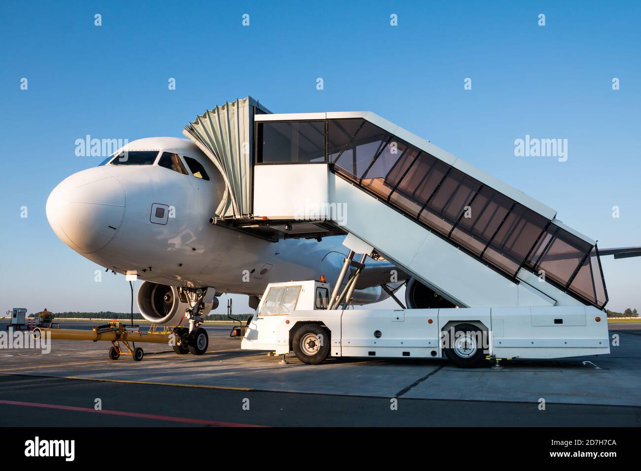 Passenger jet plane with boarding steps vehicle at the airport apron ...
