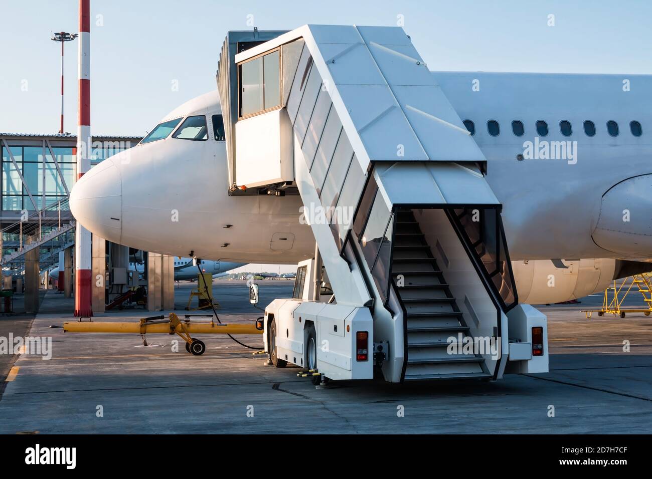 Passenger airplane with boarding steps vehicle at the airport apron ...