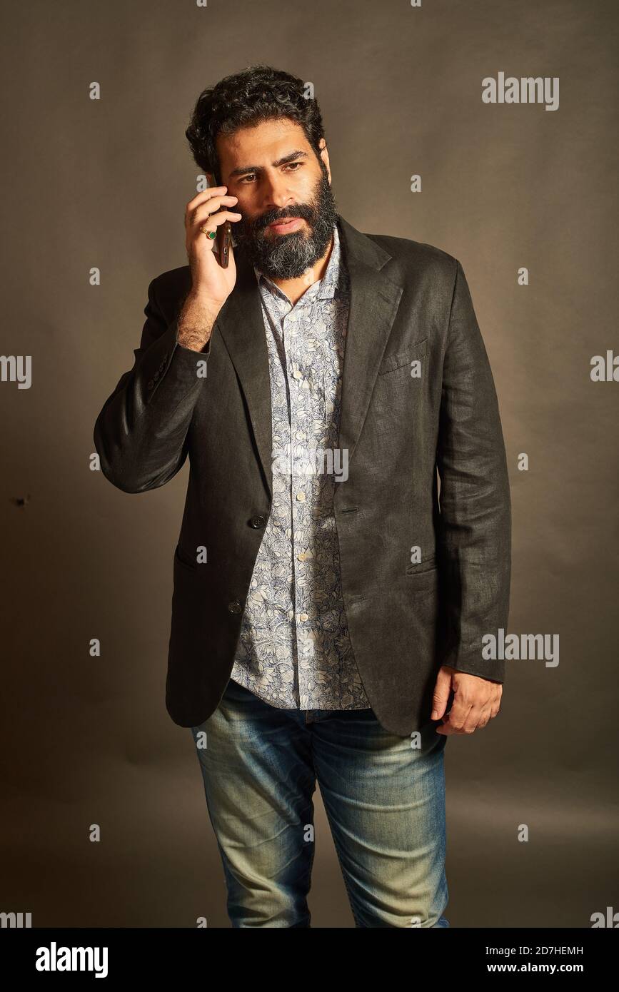 Young Indian man, in a blazer and denims, talking on his phone Stock ...