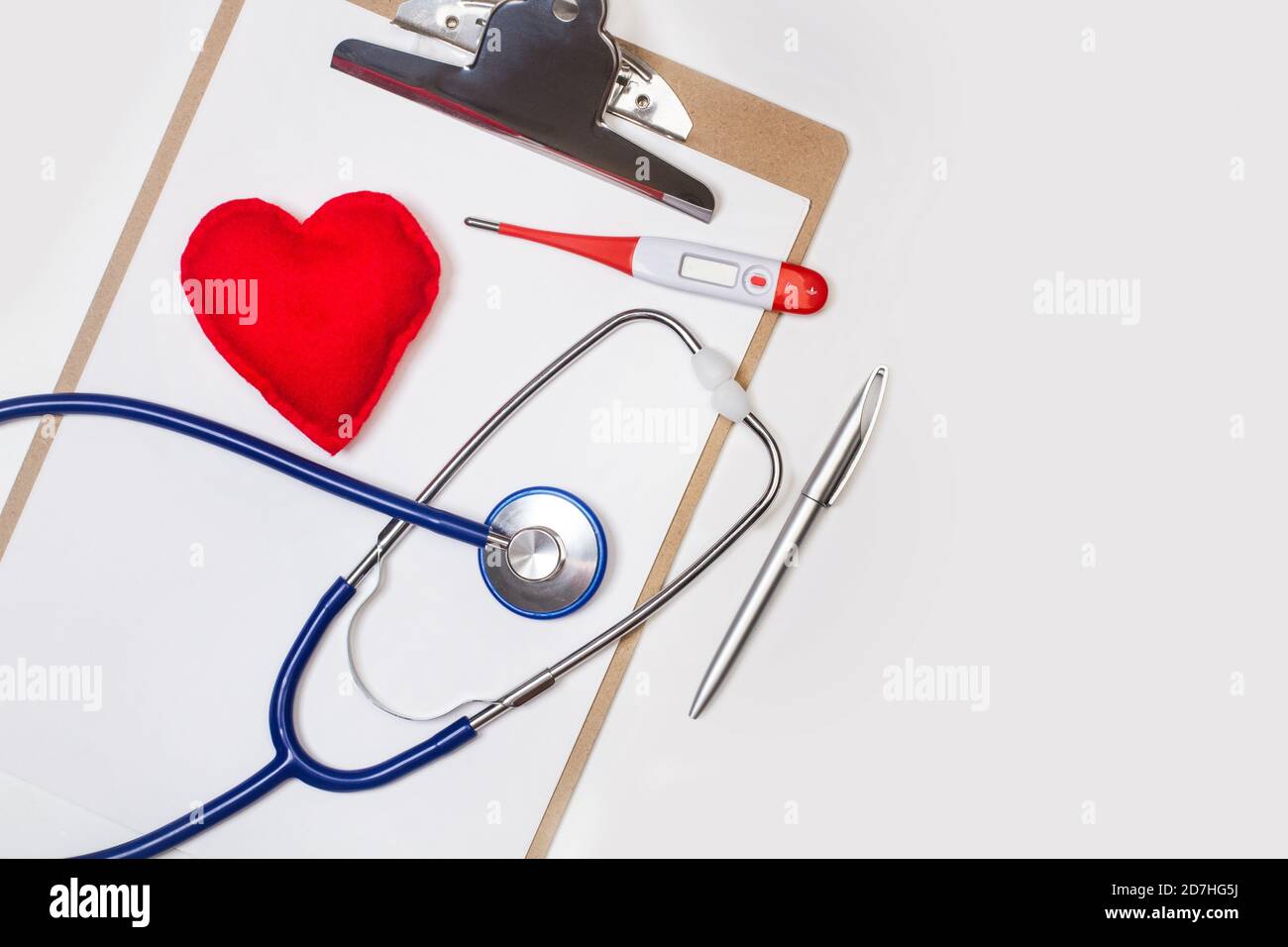 A stethoscope and a thermometer on a clipboard with a fabric red heart ...