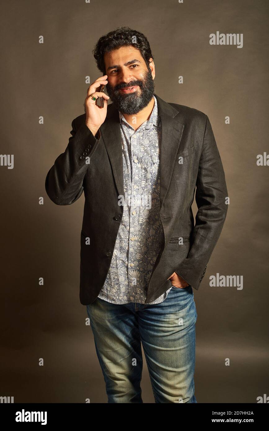 Young Indian man, in a blazer and denims, talking on his phone Stock ...