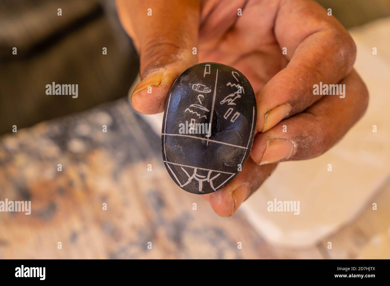 Closeup of male engraver hands writing Egyptian hieroglyphs on a black ...