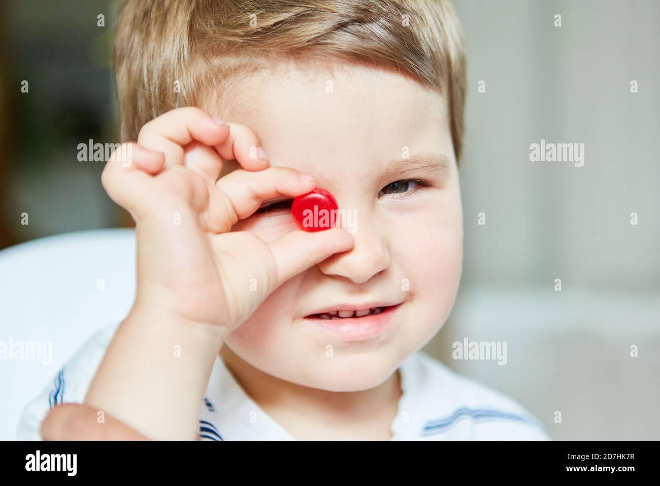 Little boy holds a red candy in one hand Stock Photo - Alamy