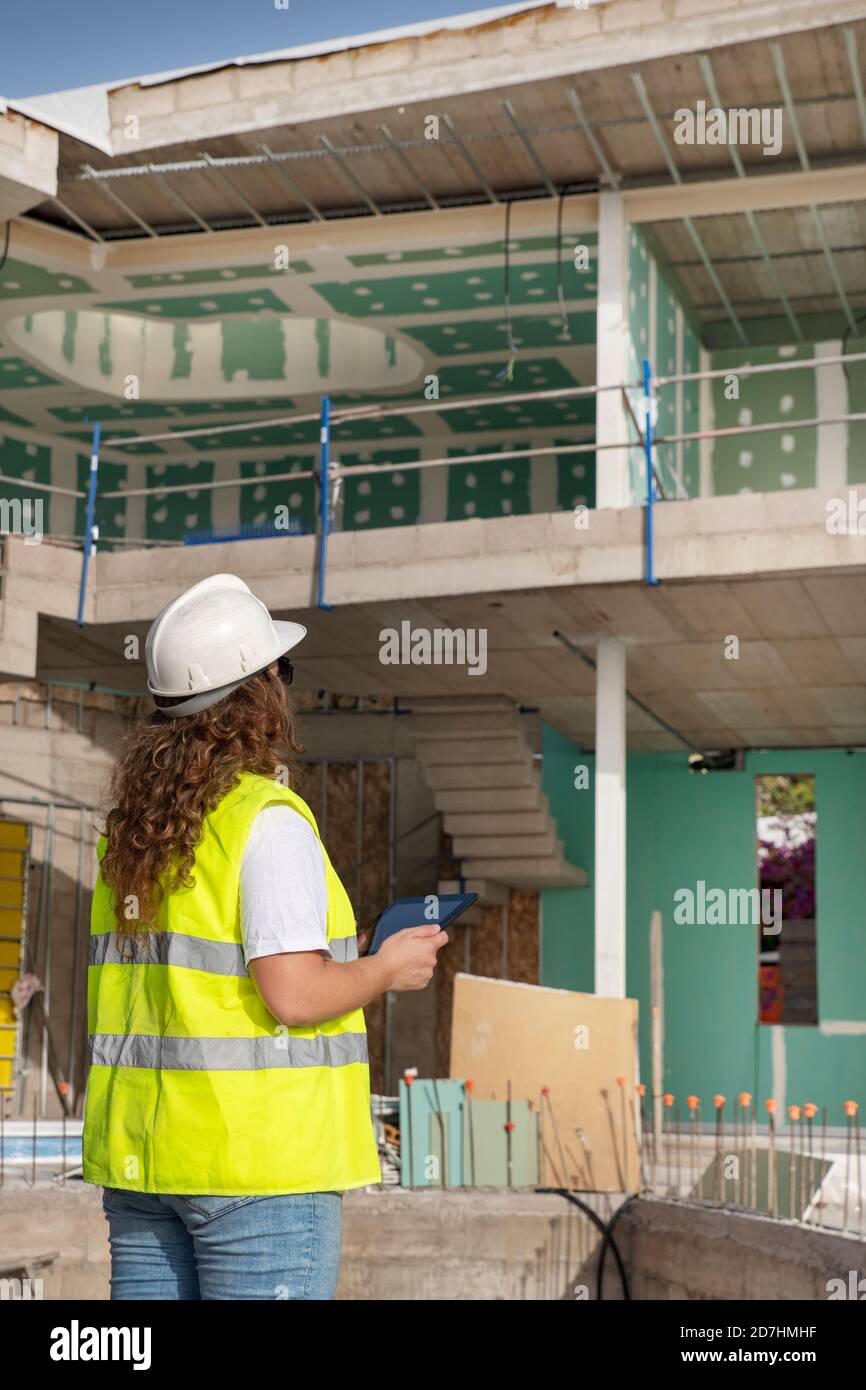 Rear view of a young female architect wearing a white helmet and a ...