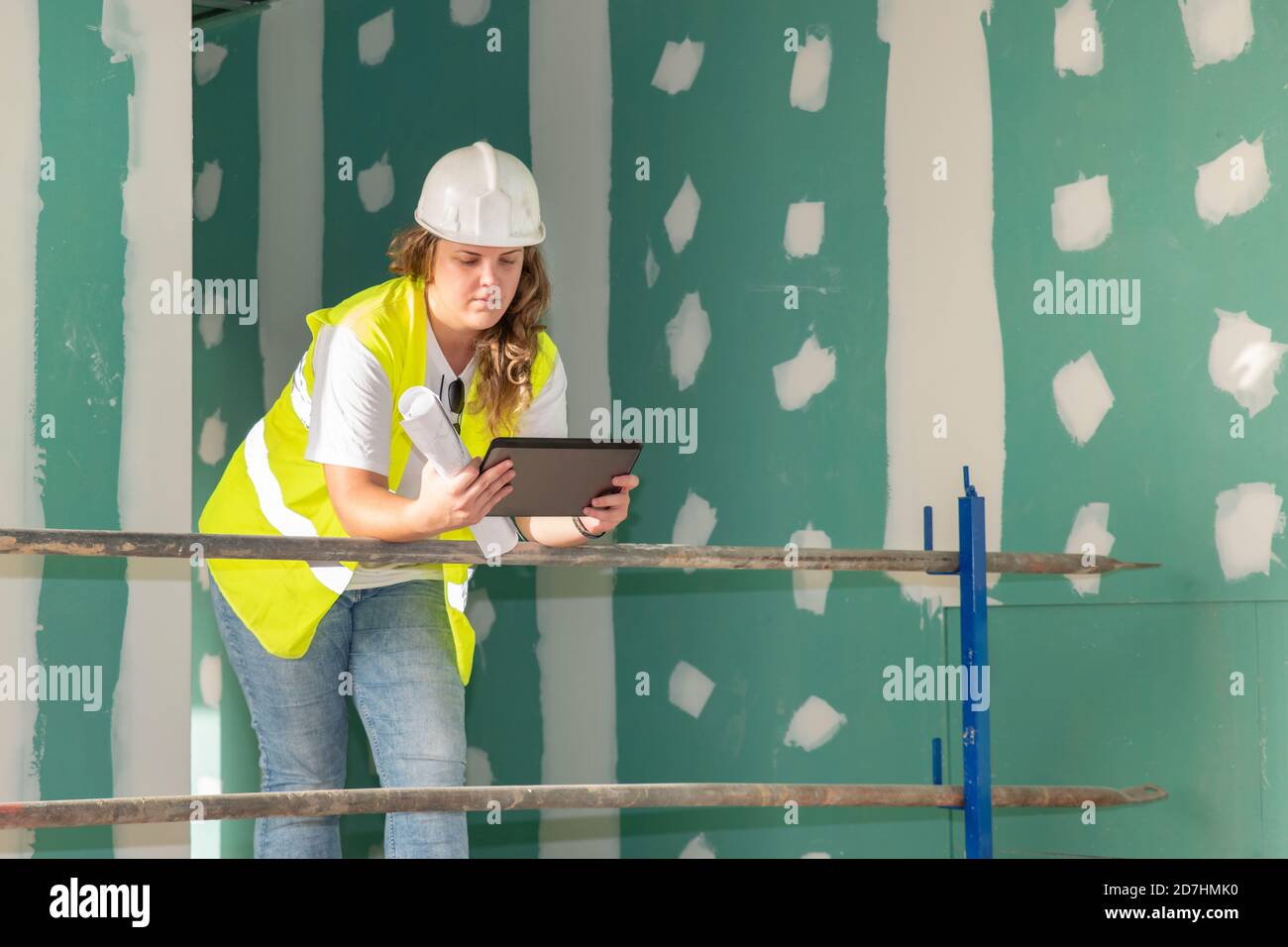 Architect wearing white helmet and a safety jacket leaning against a ...
