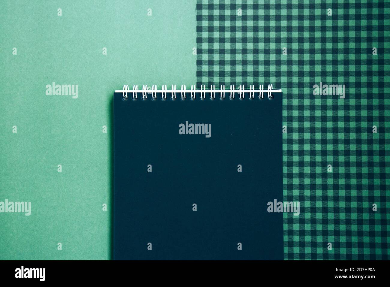 Open spiral notepad with black pages on a green checkered background ...