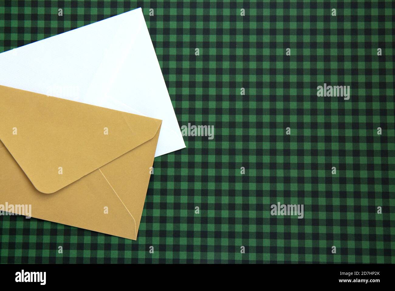 White and beige envelopes and on a green checkered background. Blank ...